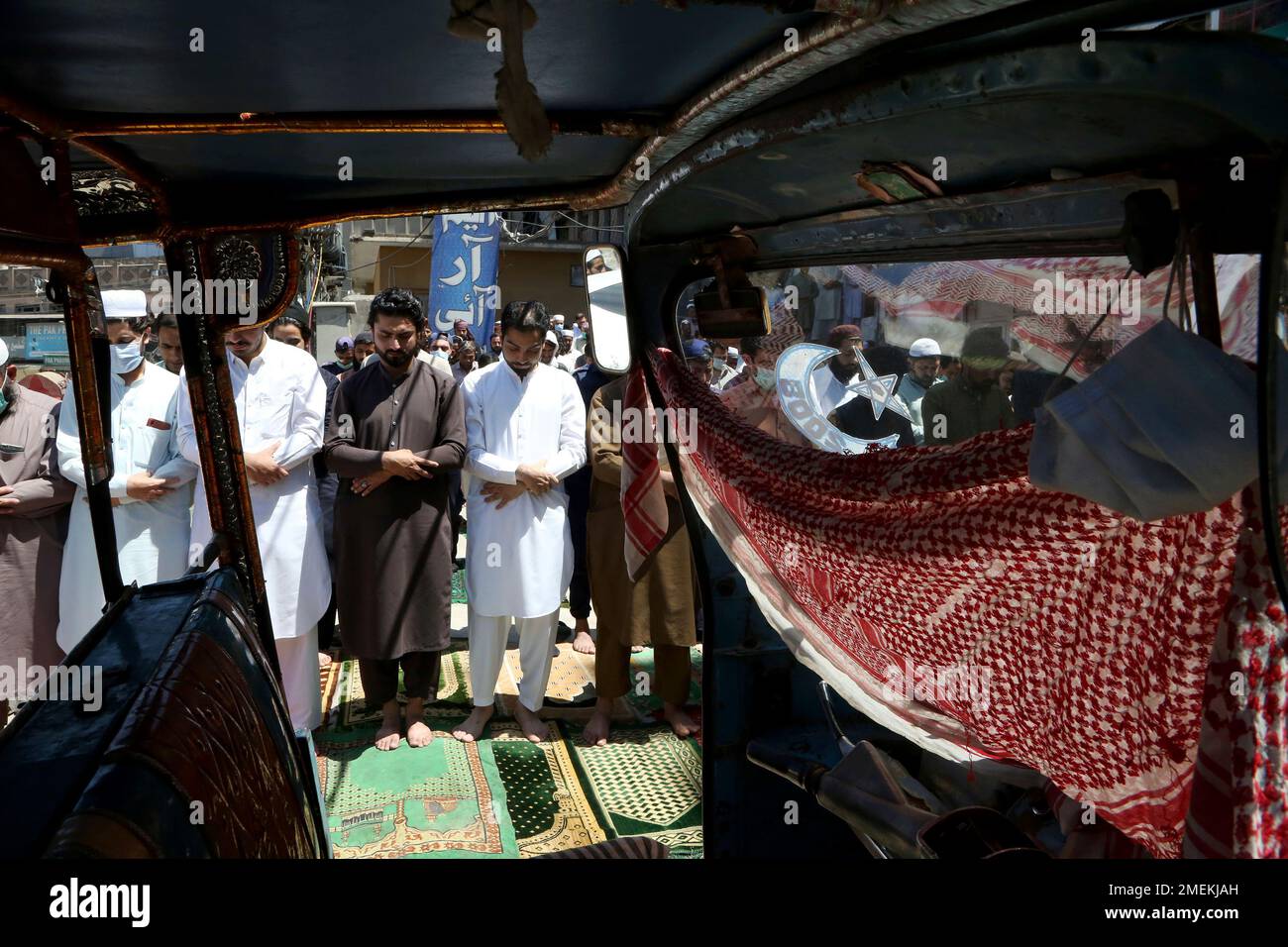 Muslims are seen though a parked auto rickshaw while performing Friday ...