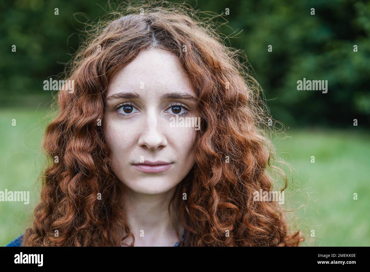 Read hair girl looking at camera outdoor - Focus on face Stock Photo ...