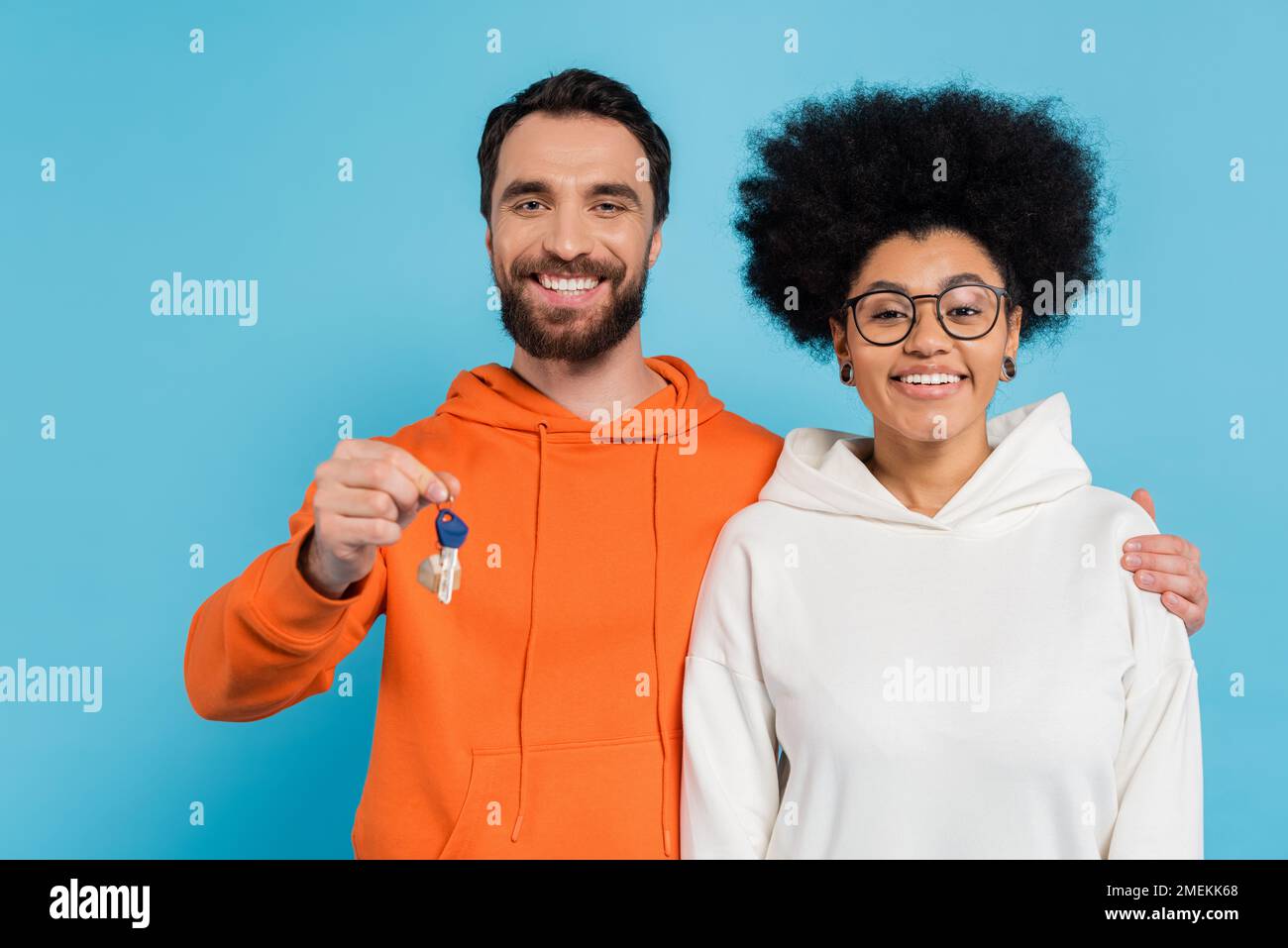 joyful bearded man hugging african american girlfriend and showing key ...