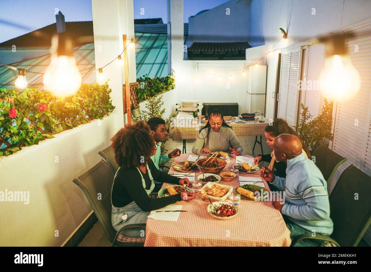 Happy african family eating dinner together at home terrace outdoor ...