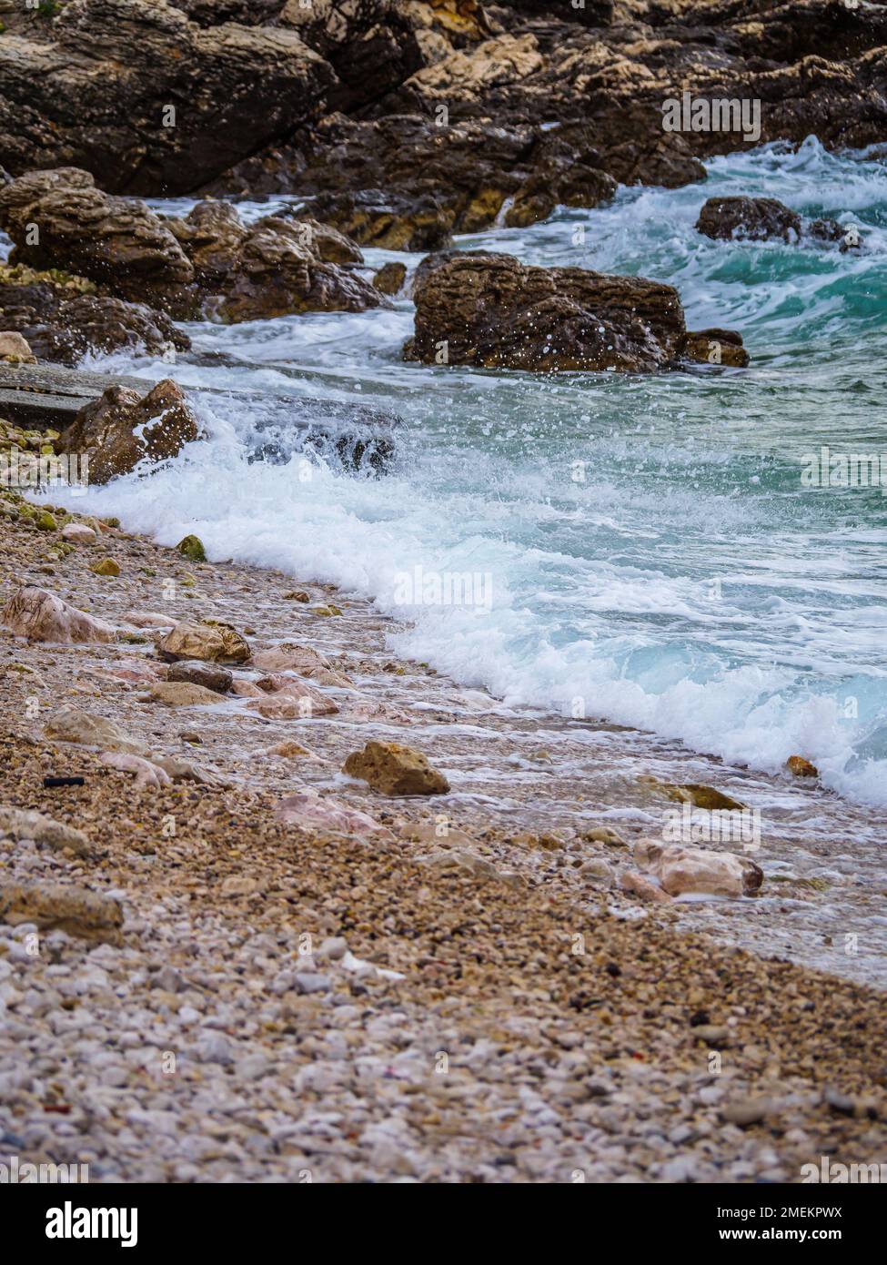 A vertical of water splash, foamy turquoise sea waves splashing onto a ...
