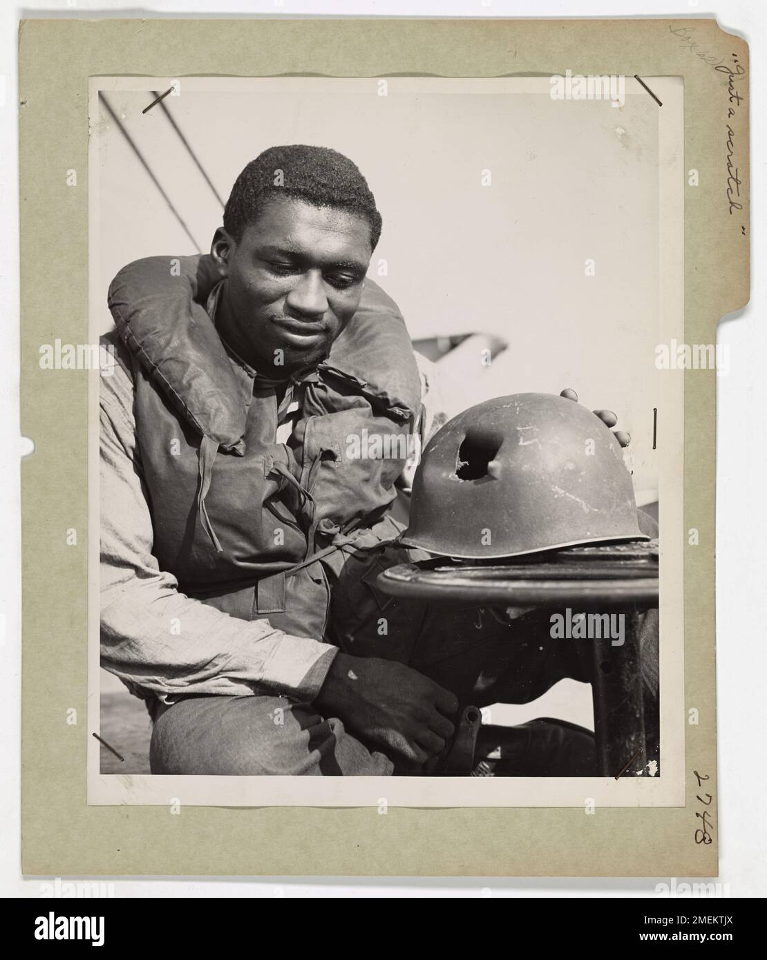 Coast Guardsman Charles W. Tyner inspects a shrapnel hole in his helmet ...