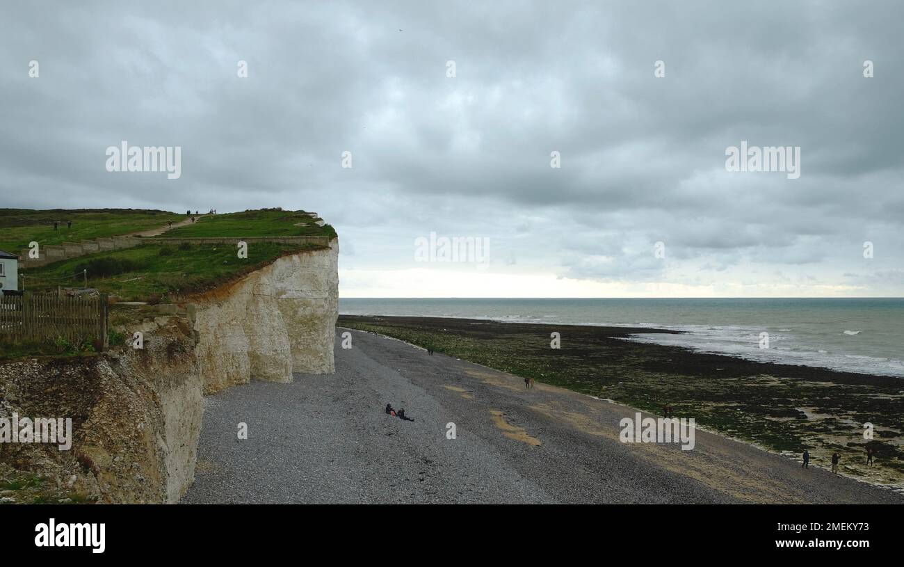 A view of the cliff fall of birling gap beach with people sitting on it ...