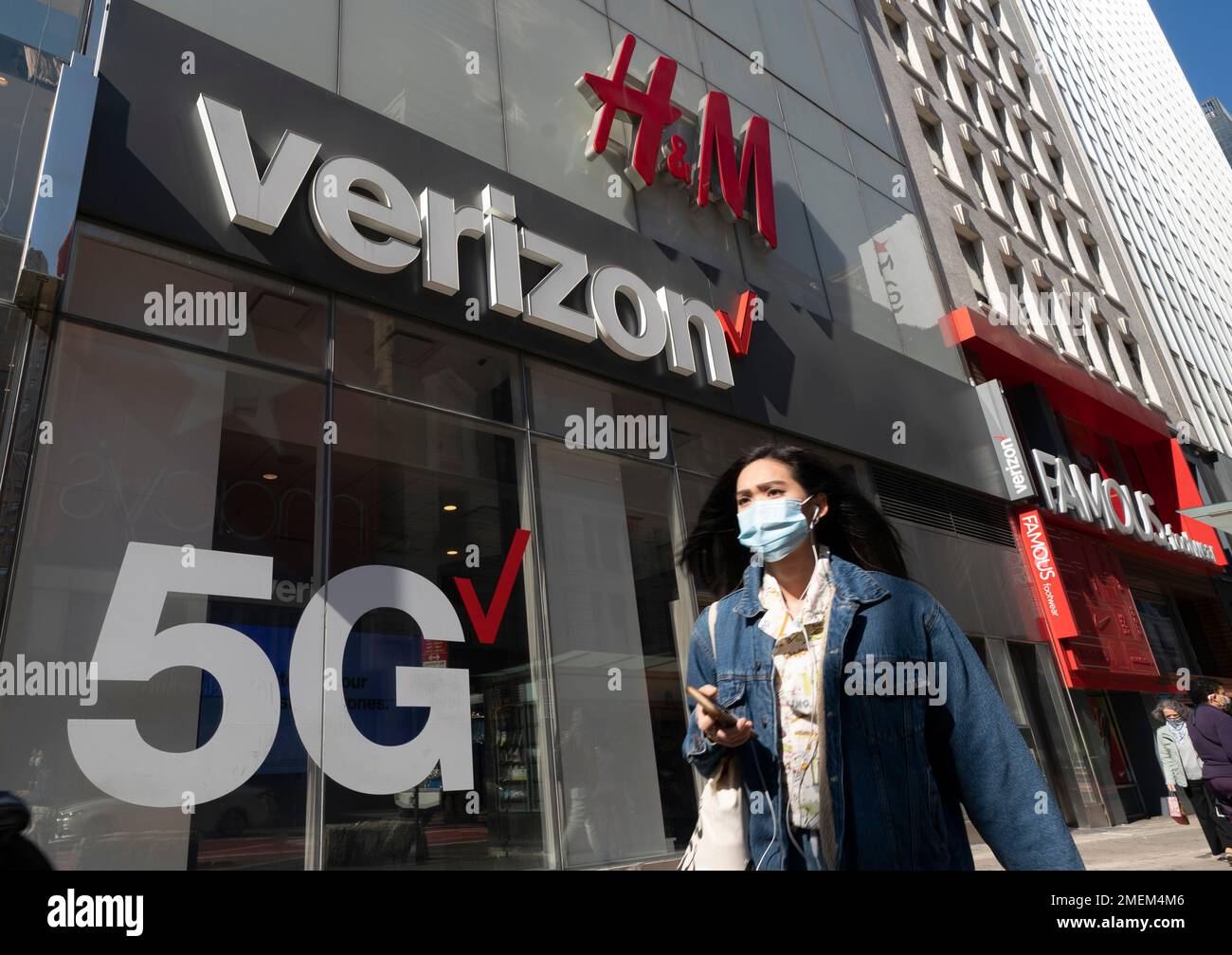 A woman uses a mobile phone as she walks by a Verizon store, Monday ...
