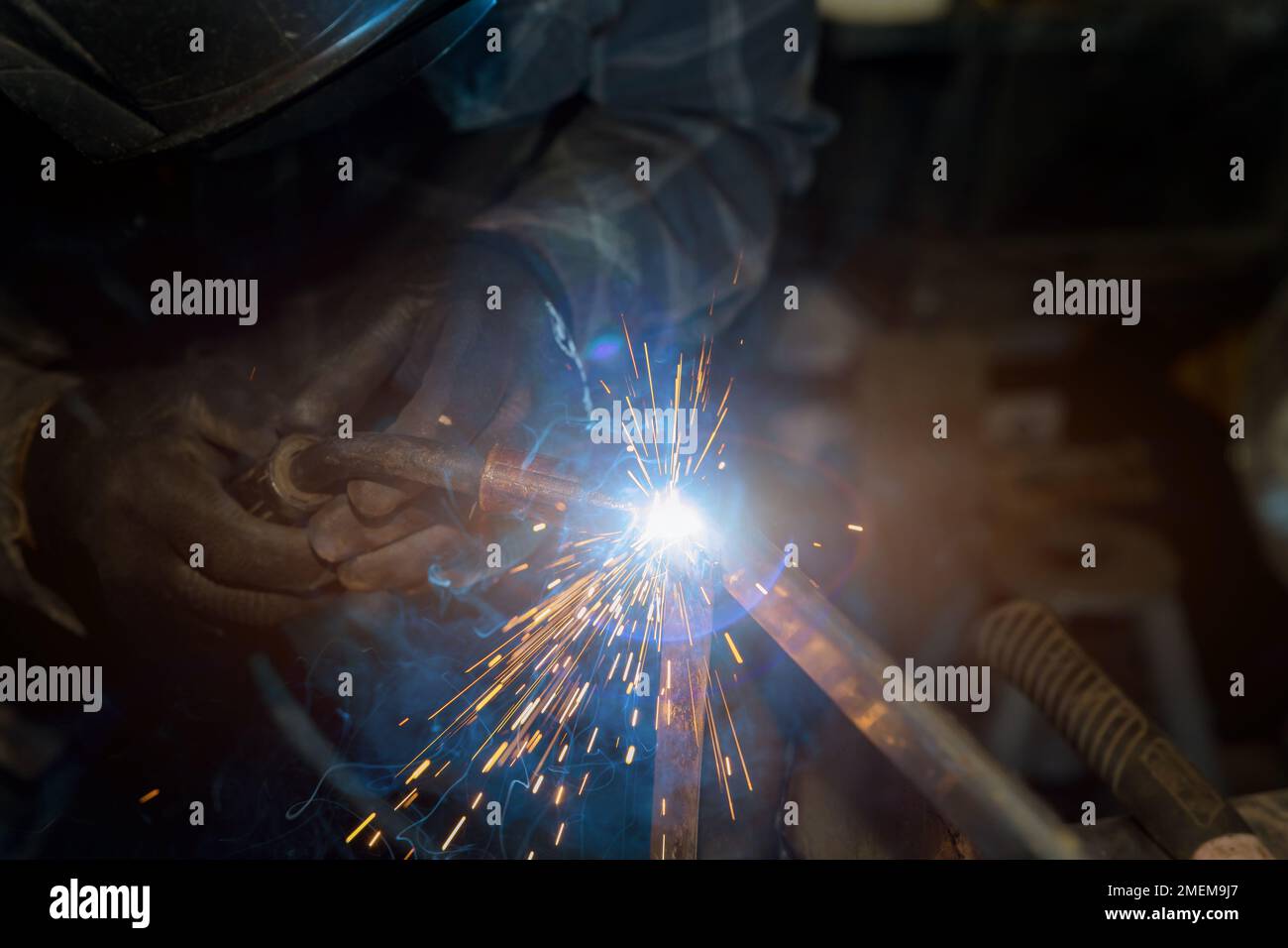 Worker welding metal with sparkles on it, using semi automatic welding ...