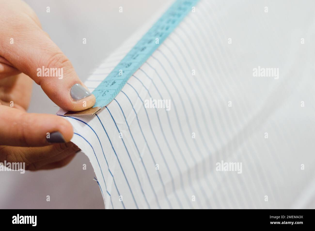 close-up of a female hand extending a tape measure along the edge of a ...