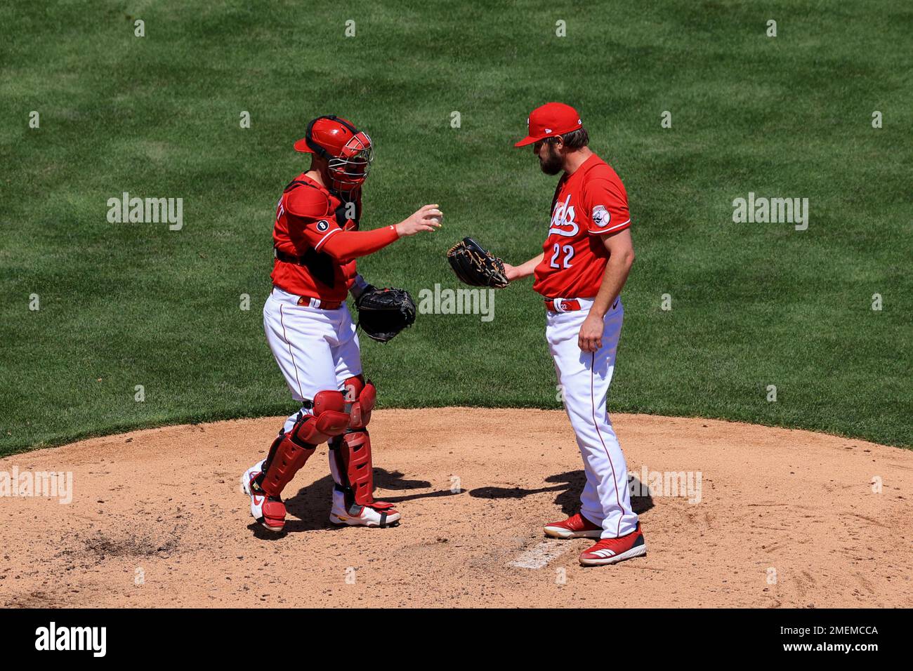 Cincinnati Reds' Tucker Barnhart, left, hands the ball to teammate Wade ...