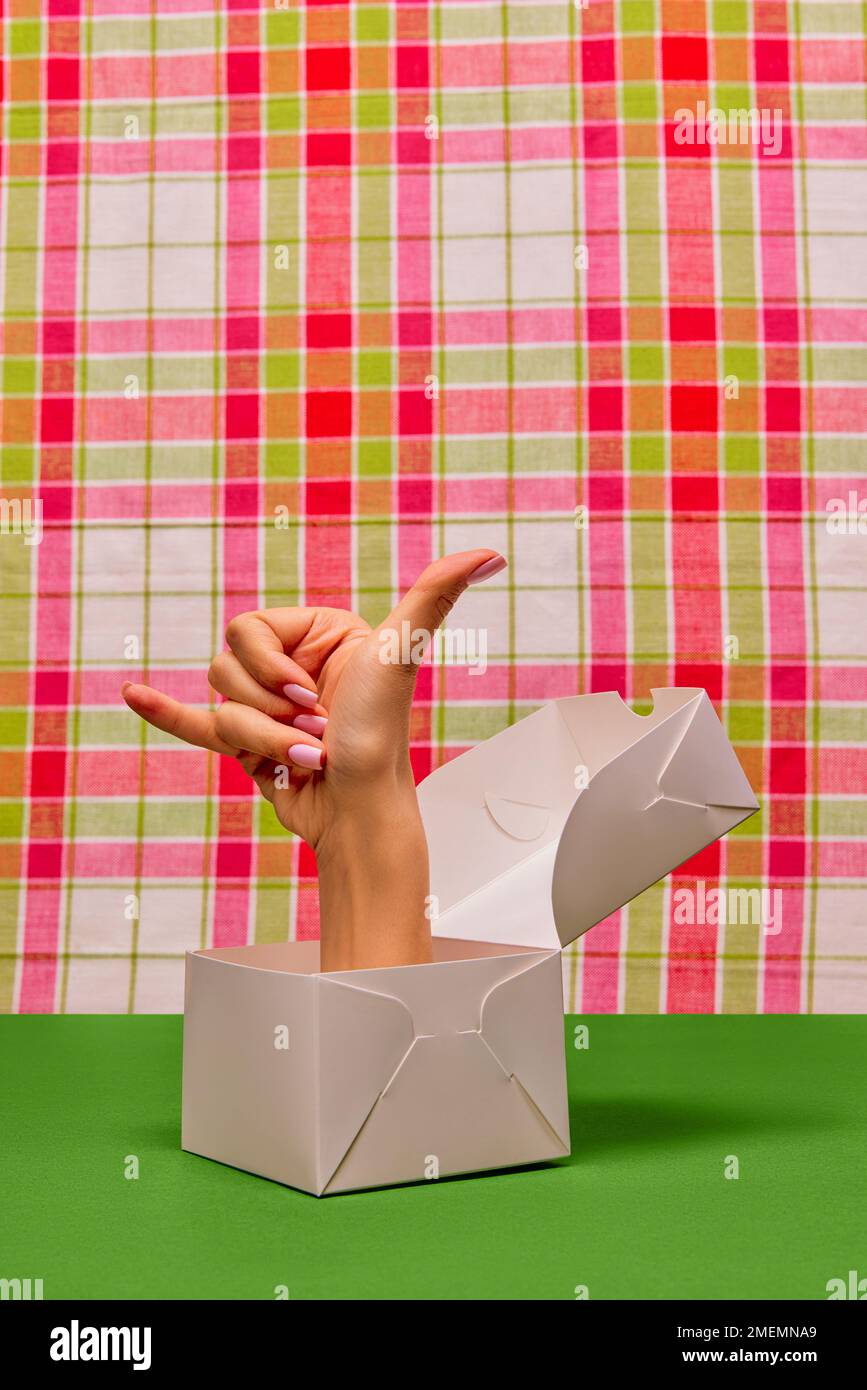 Pop art photography. Female hand sticking out food box and showing hang ...