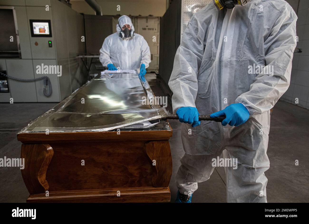 Funeral workers open the coffin of a COVID-19 victim to place his ...