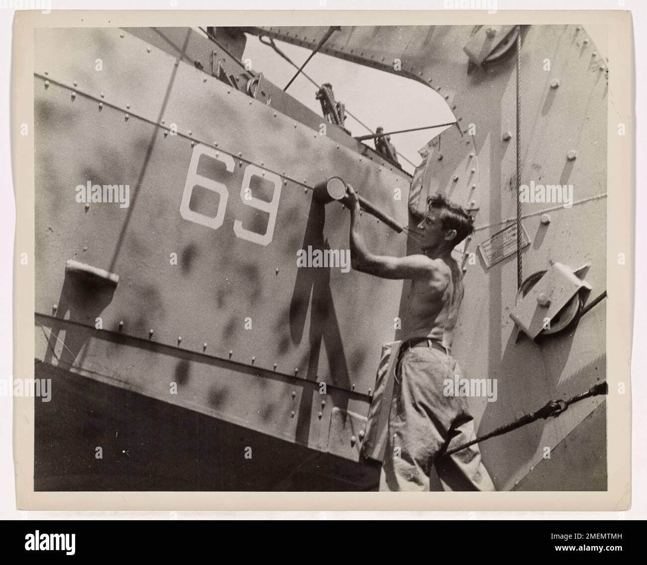 A Coast Guardsman applies camouflage to a Coast Guard-manned LST ...