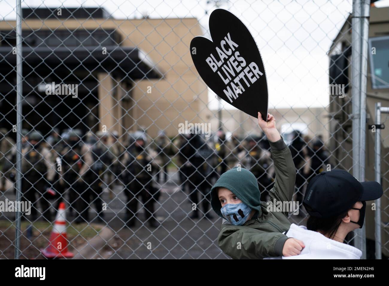Demonstrators gather as authorities guard a perimeter fence during a ...