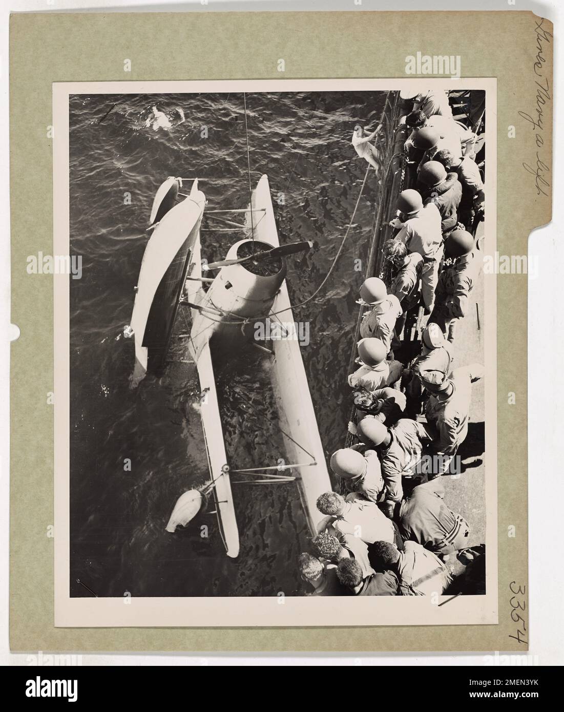 This image shows a Navy seaplane being hoisted aboard a Coast Guard ...