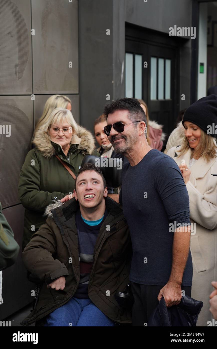 Judge Simon Cowell poses for a photo with a fan as he arrives for the ...