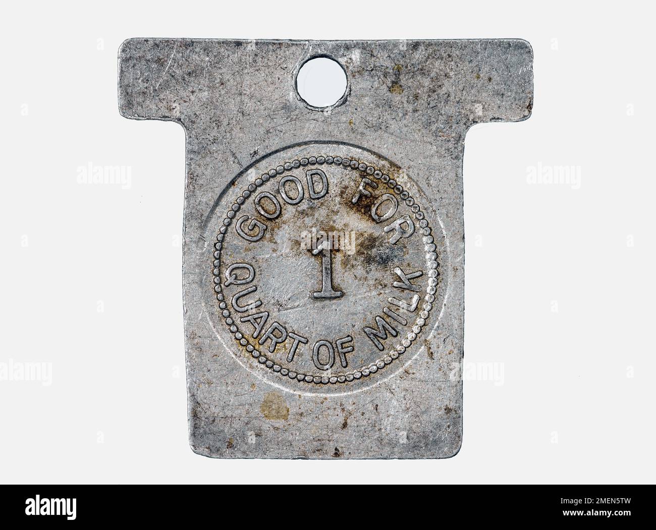 An old tarnished and dirty milk token on a white background. The ...