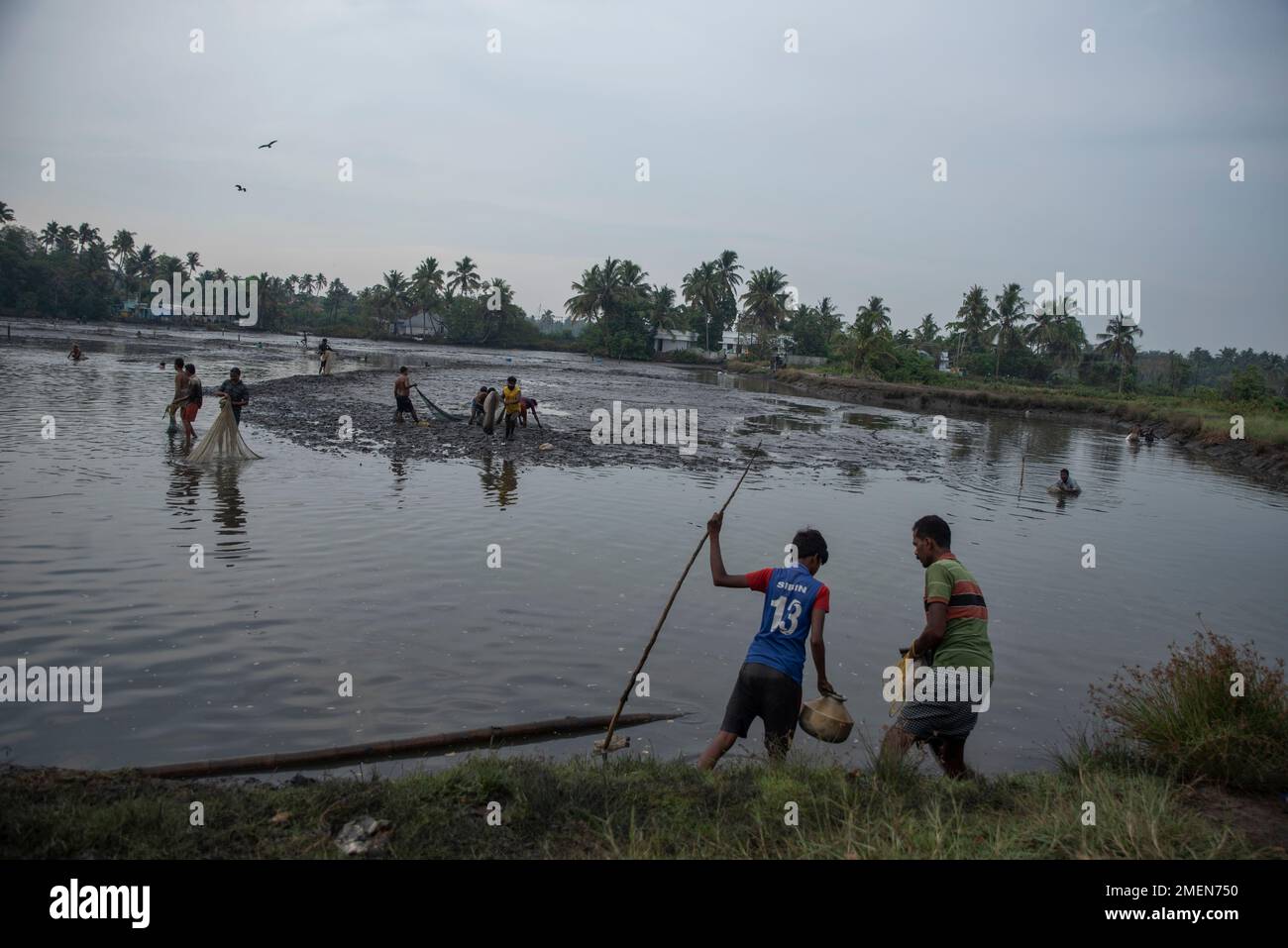People fish at a tidal swamp after water is drained at the end of prawn ...