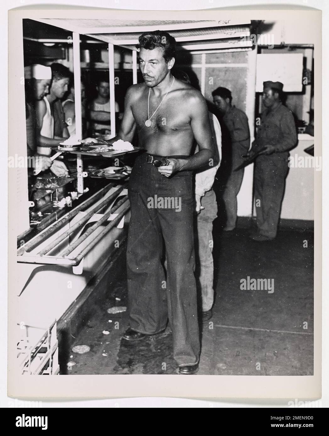 A photograph shows actor Cesar Romero in a mess line, likely during his ...