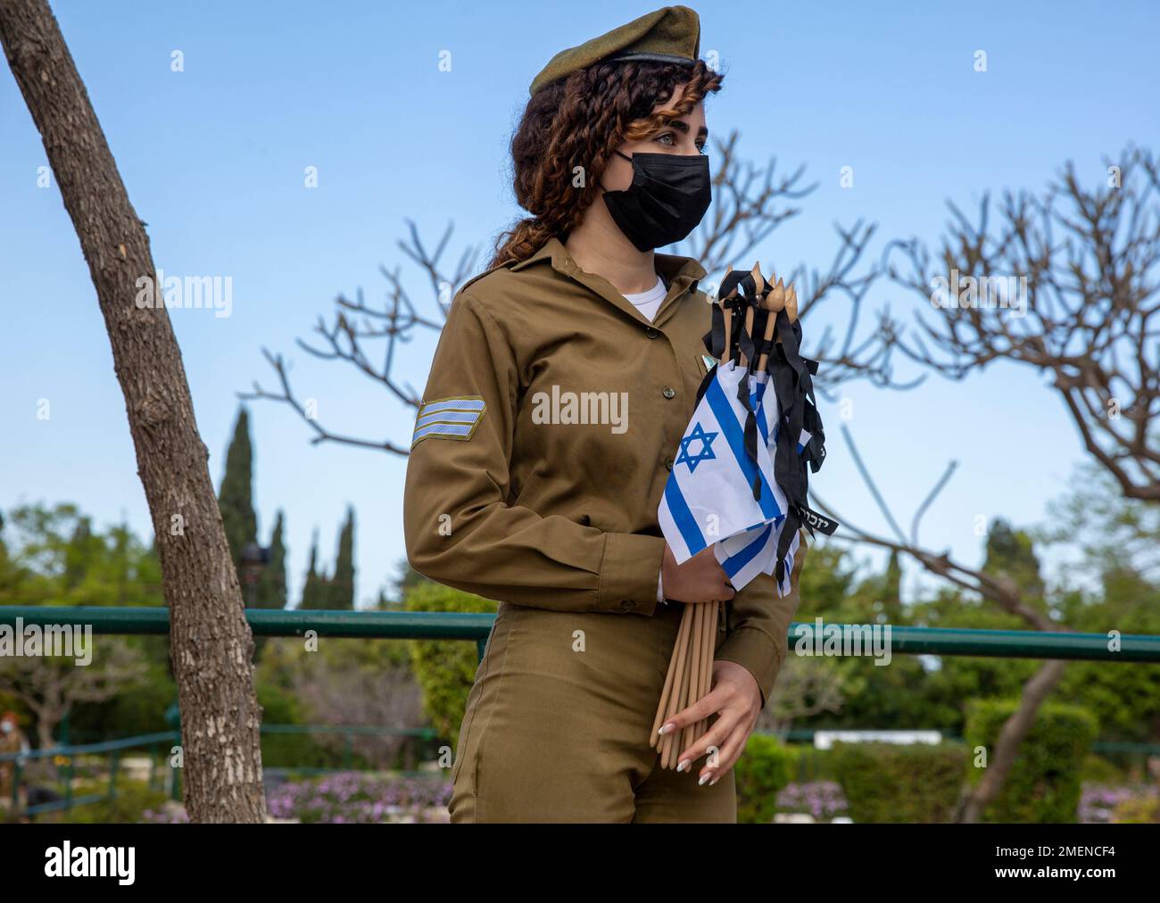 An Israeli soldier holds flags with black ribbons attached as she ...