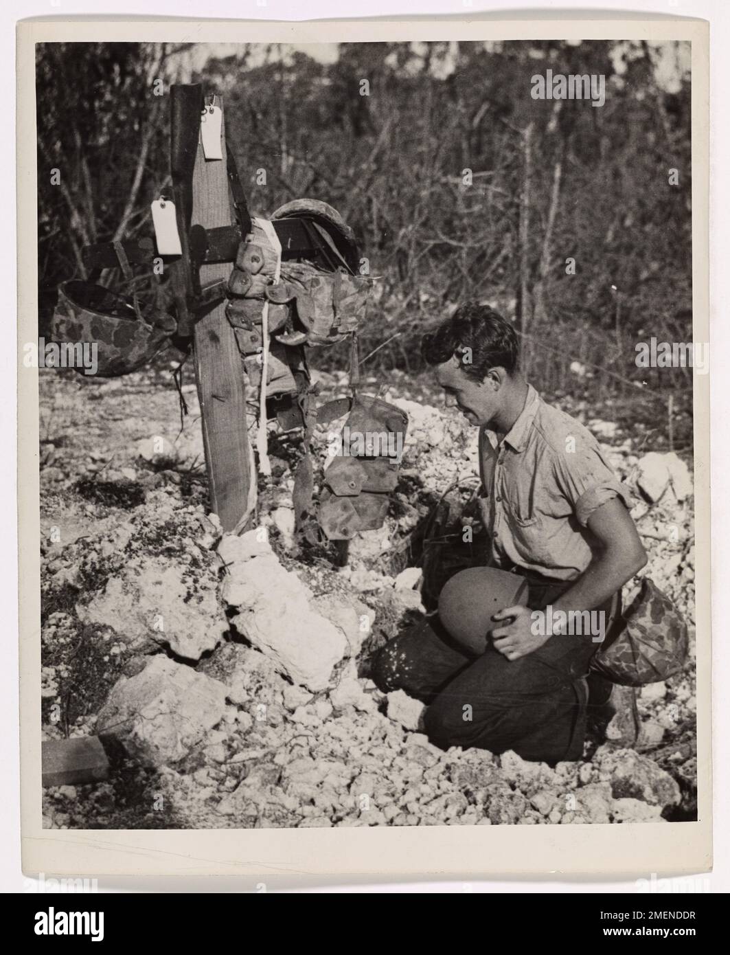 A Coast Guardsman kneels beside the grave of Marine Private First Class ...