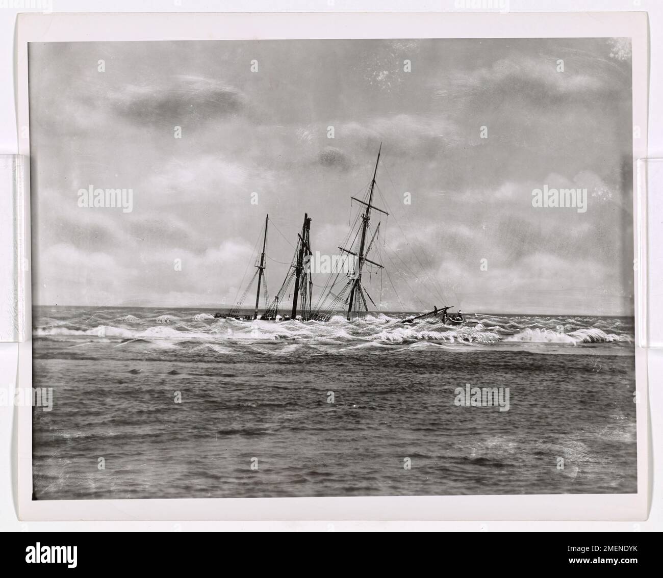 Coast Guardsmen in a small boat assist a sinking sailing ship in this ...
