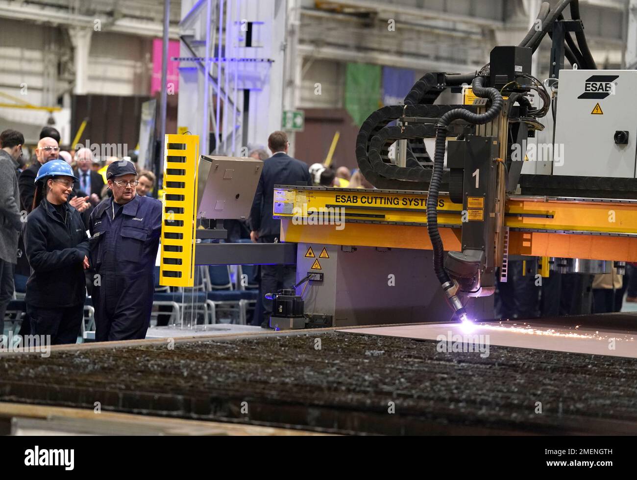 Workers look on as the first cut of steel for the Royal Navy frigate ...