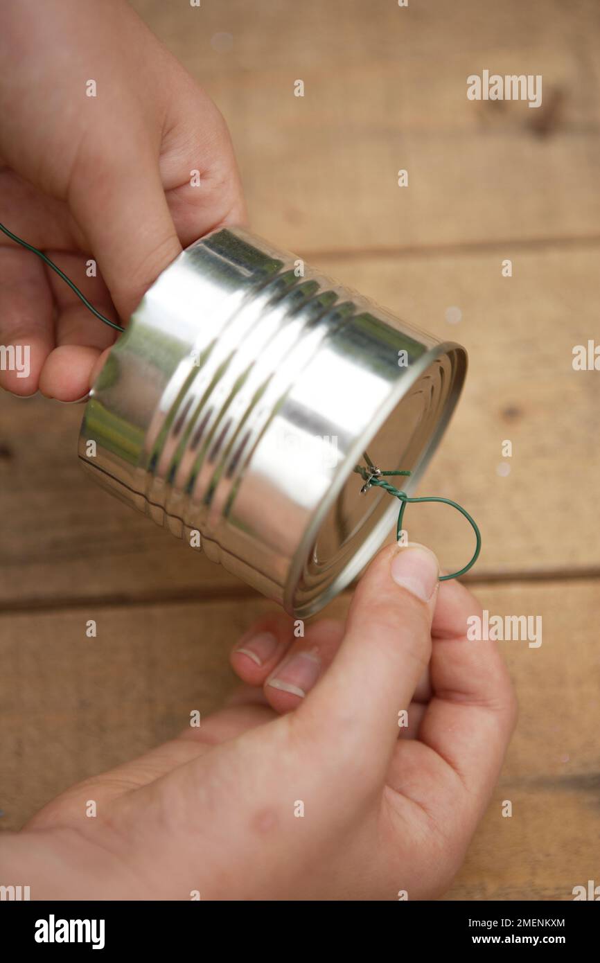 wire threaded through hole of tin can Stock Photo - Alamy