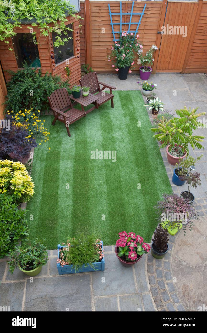 Small garden with wooden chairs and small table on artificial lawn ...