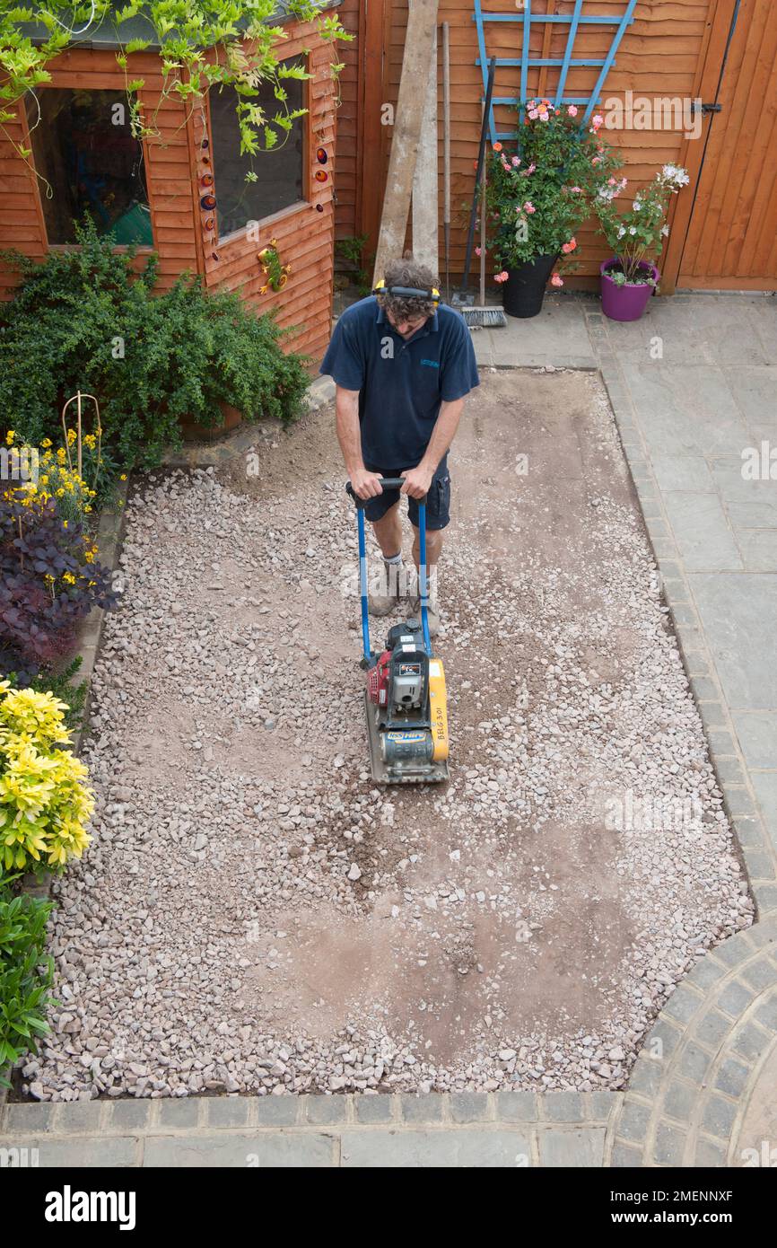 Using a machine to flatten and compress the layers of soil and grit ...