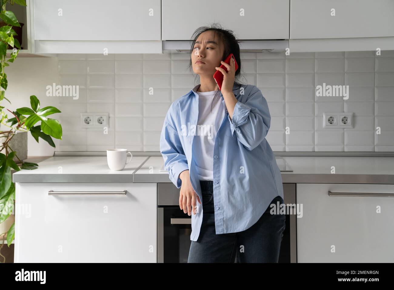 Young dissatisfied displeased Asian woman talking on mobile phone at ...