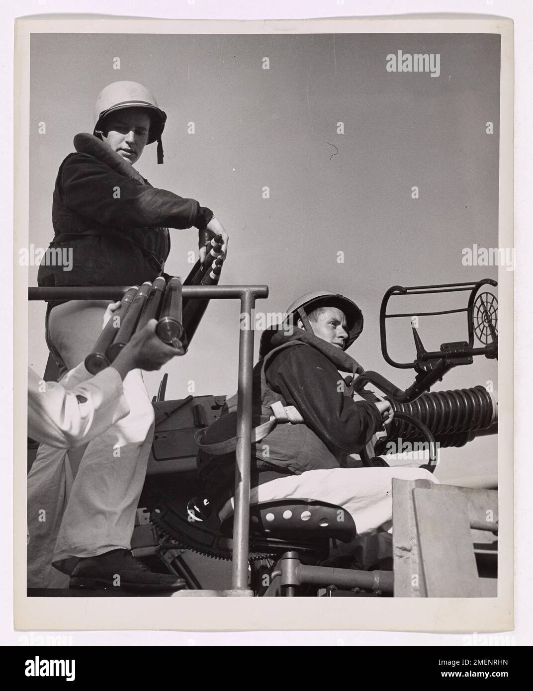 Coast Guardsmen are shown loading a large gun, preparing for defensive ...