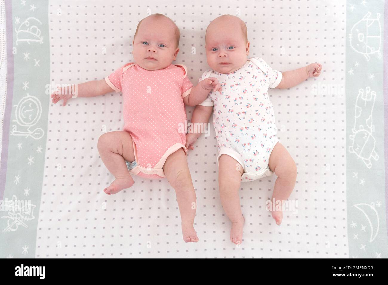 Twin baby girls both lying on back, 13 weeks Stock Photo - Alamy