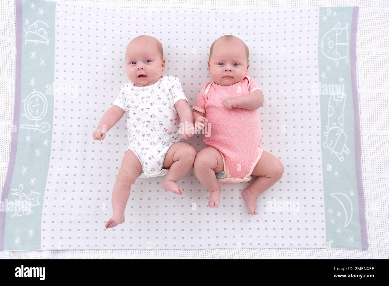 Twin baby girls lying together on mat, overhead view, 13 weeks Stock Photo - Alamy