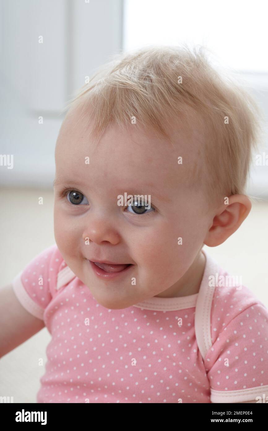 Smiling baby girl (9 months), three-quarter front view Stock Photo - Alamy