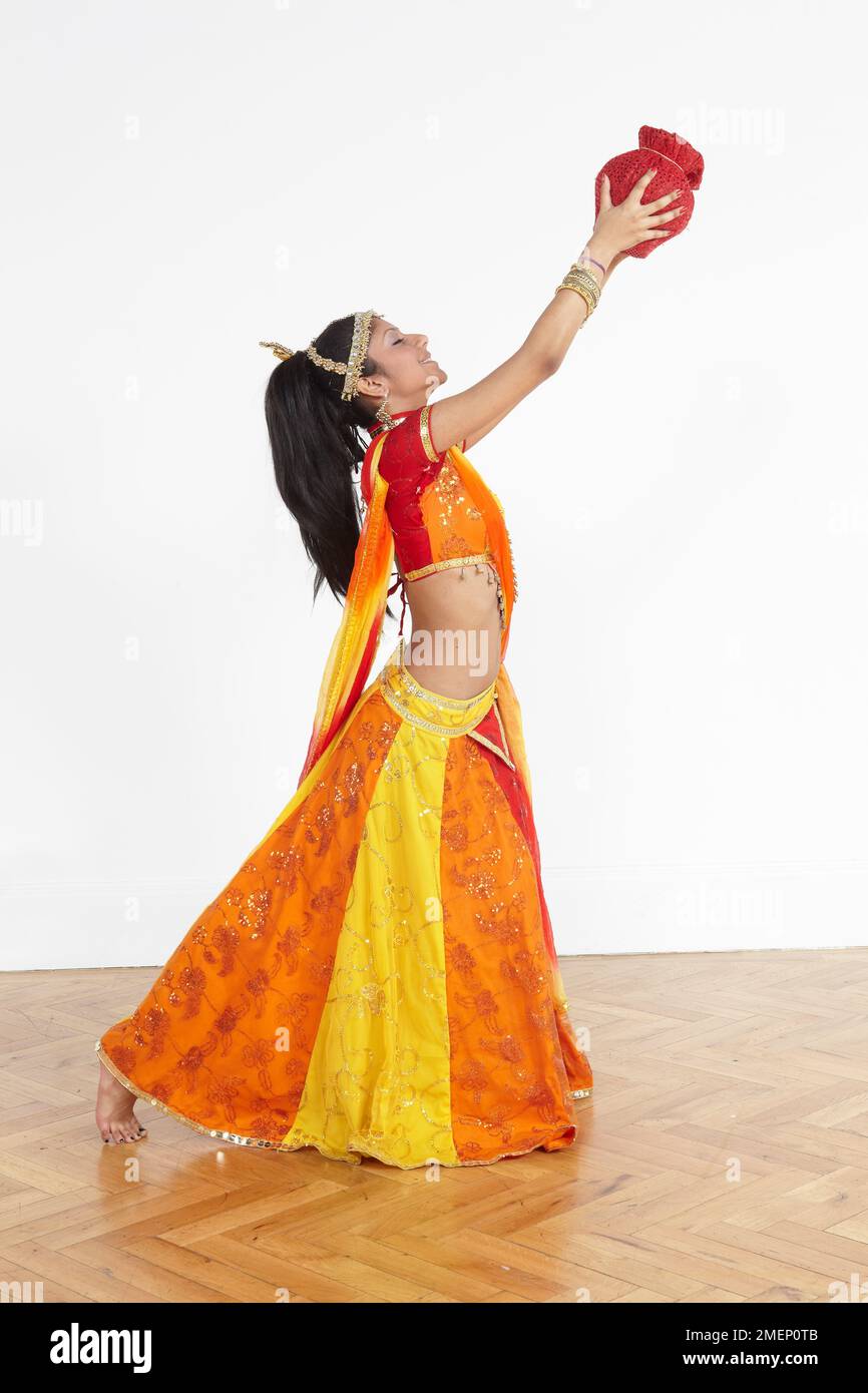 Barefoot female dancer in a brightly coloured traditional dress ...