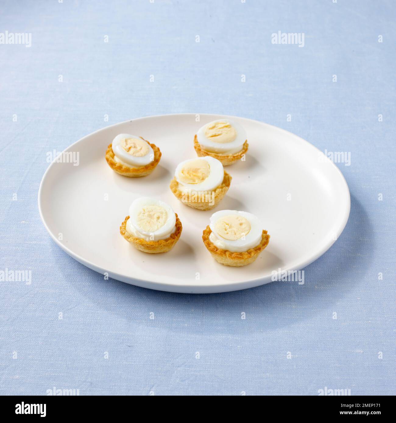 Hard boiled egg croustade canapes on large white plate Stock Photo - Alamy