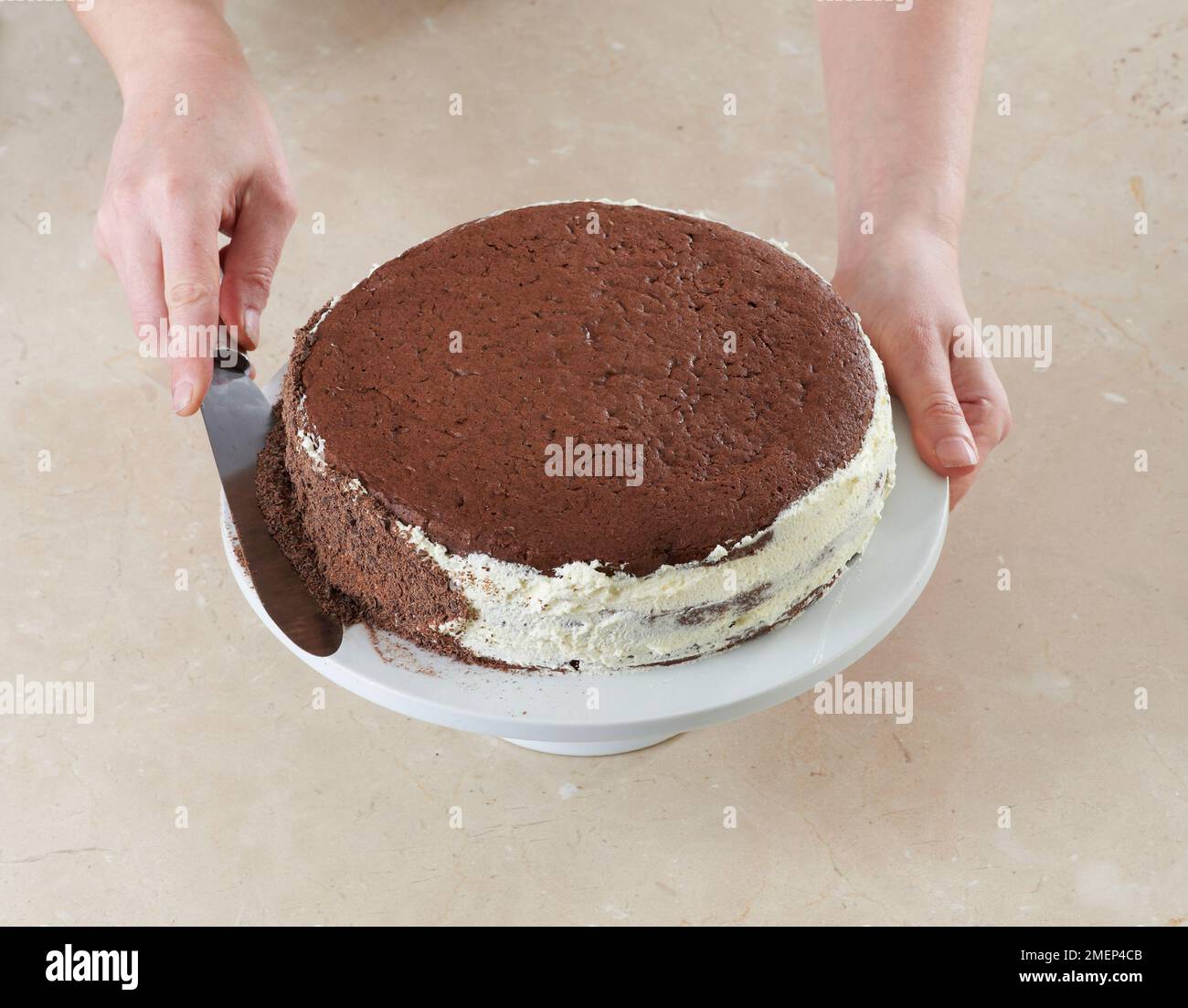 Black Forest Gateau, pressing grated chocolate onto creamy sides with ...