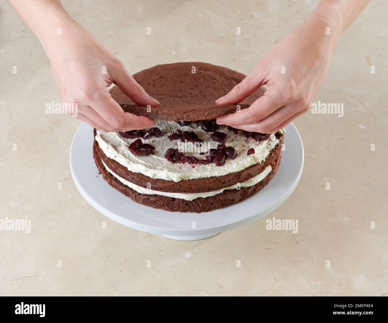 Black Forest Gateau, pressing down final layer of sponge on whipped ...