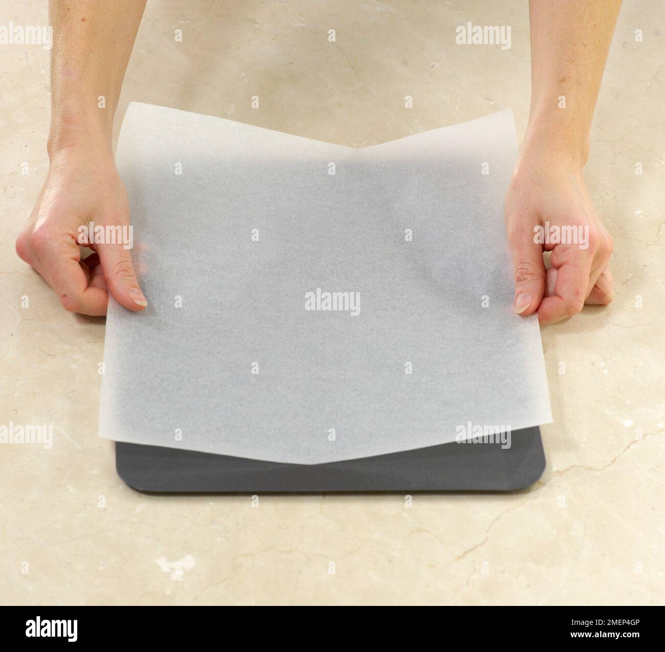 Placing baking parchment on baking sheet or tray Stock Photo - Alamy