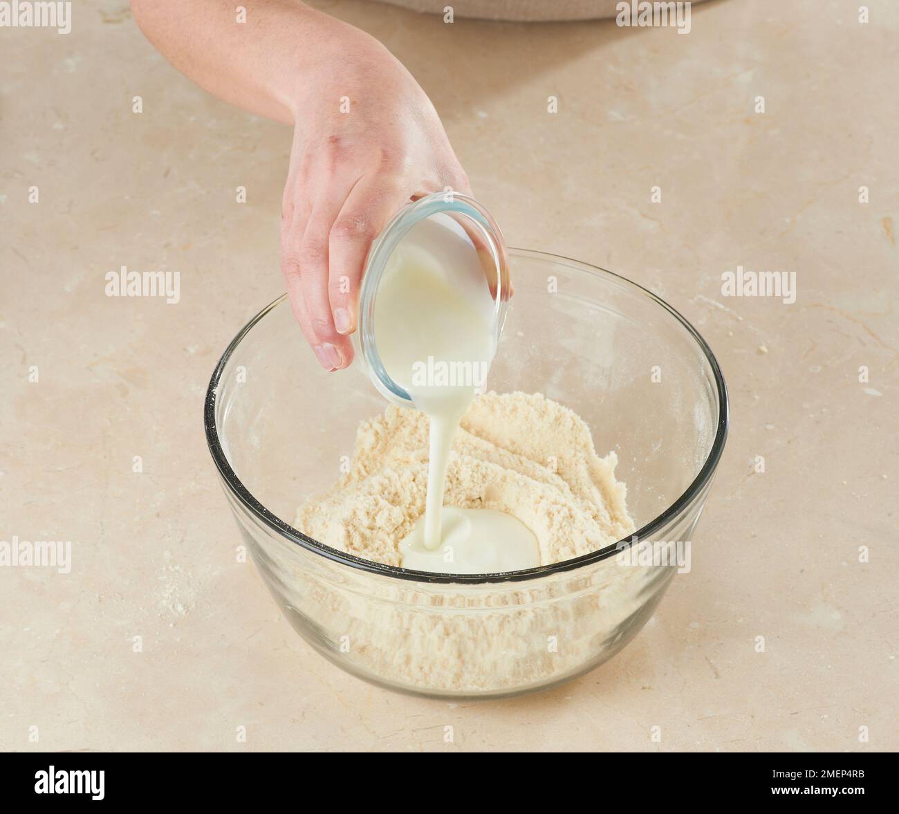 Pouring milk on scone ingredients in glass mixing bowl Stock Photo - Alamy