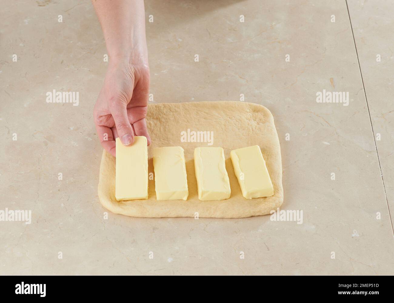 Making Danish Pastries, laying butter slices on one half of dough Stock ...