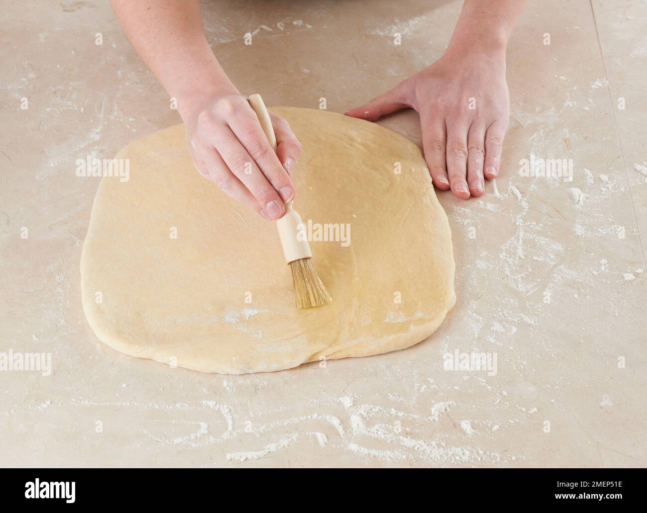 Making Cinnamon Rolls, brushing rolled out dough with melted butter ...
