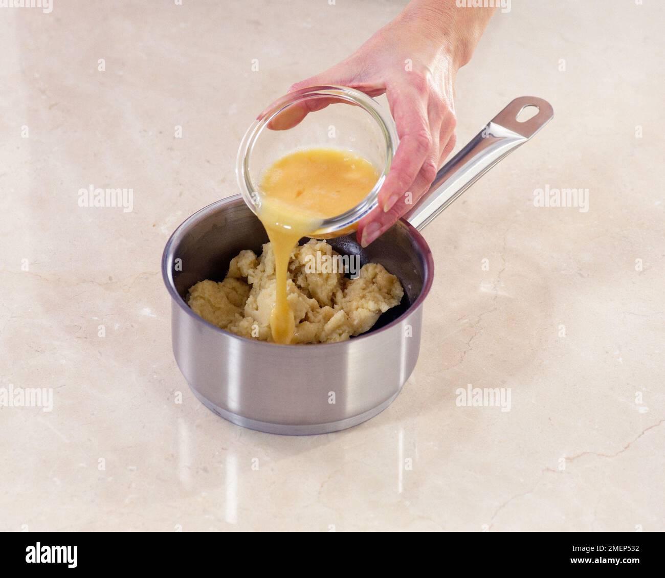 Making Profiteroles, adding eggs to the mixture Stock Photo - Alamy