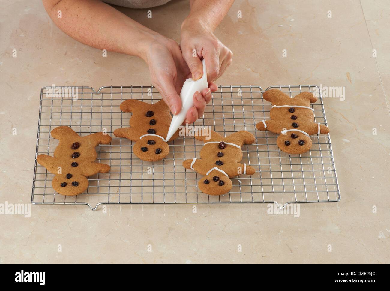 Making Gingerbread Men, decorating the biscuits with piped icing Stock ...