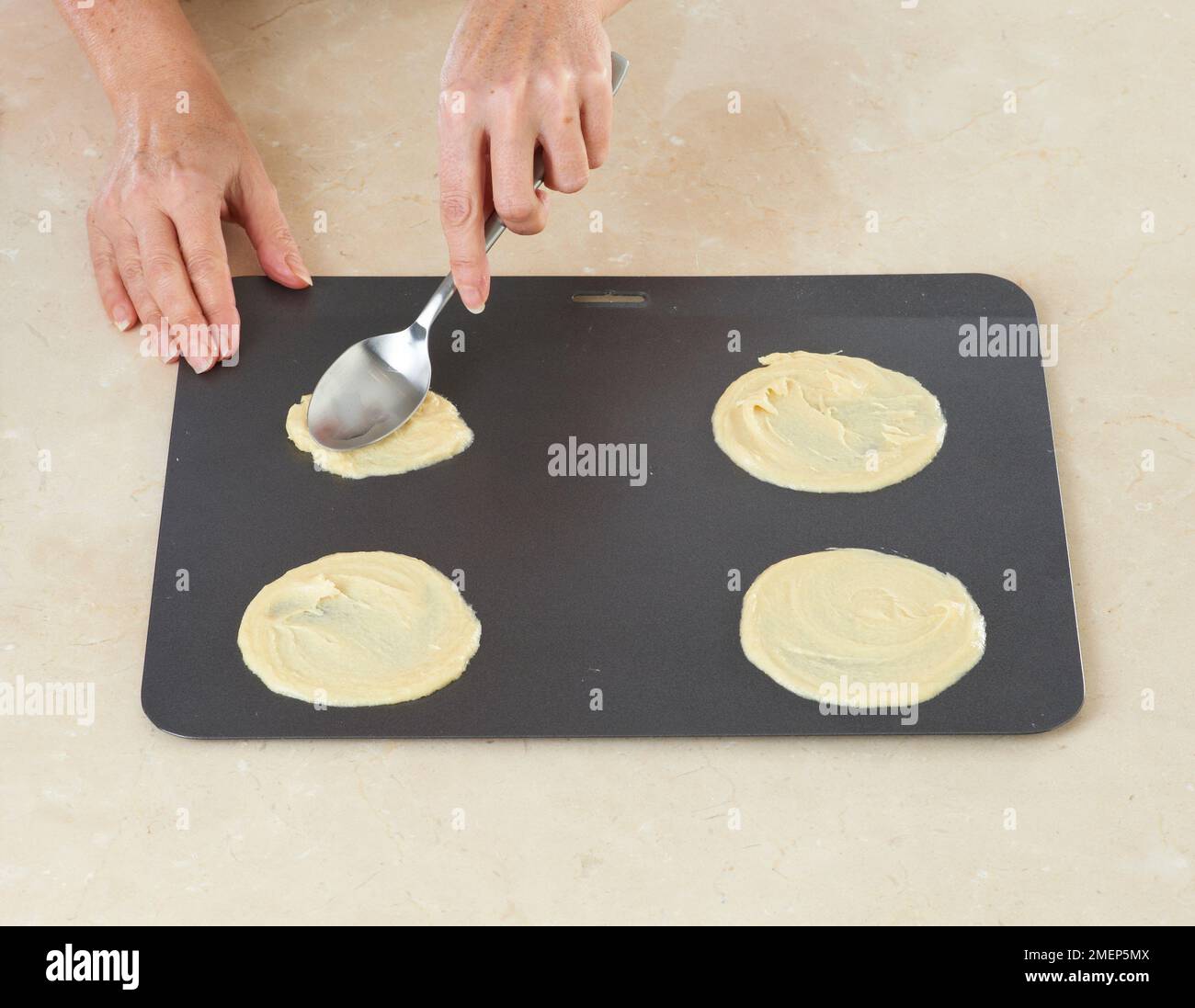 Flattening Tuile mixture with soon on baking tray Stock Photo - Alamy