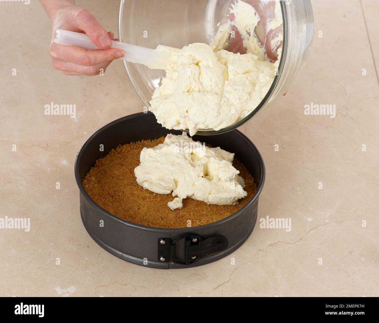 Making Lemon Cheesecake, tipping cheese mixture onto chilled biscuit ...