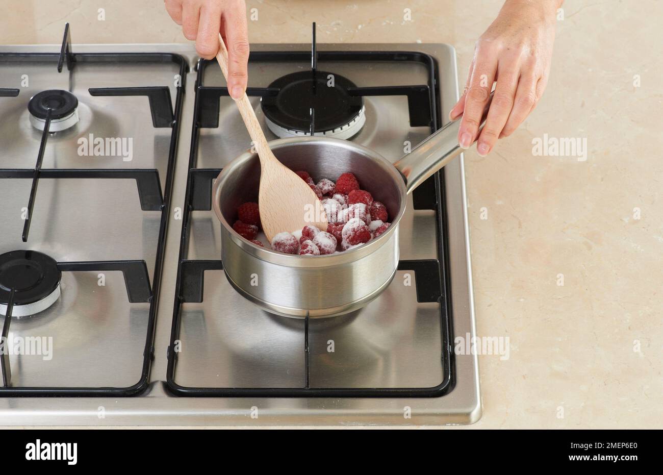 Cooking raspberries and caster sugar in pan, to make raspberry filling ...