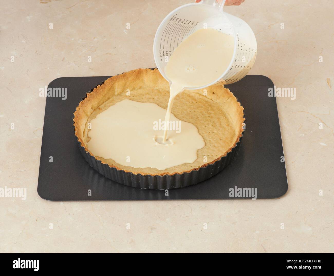 Custard Tart, pouring the filling into the tart case Stock Photo - Alamy