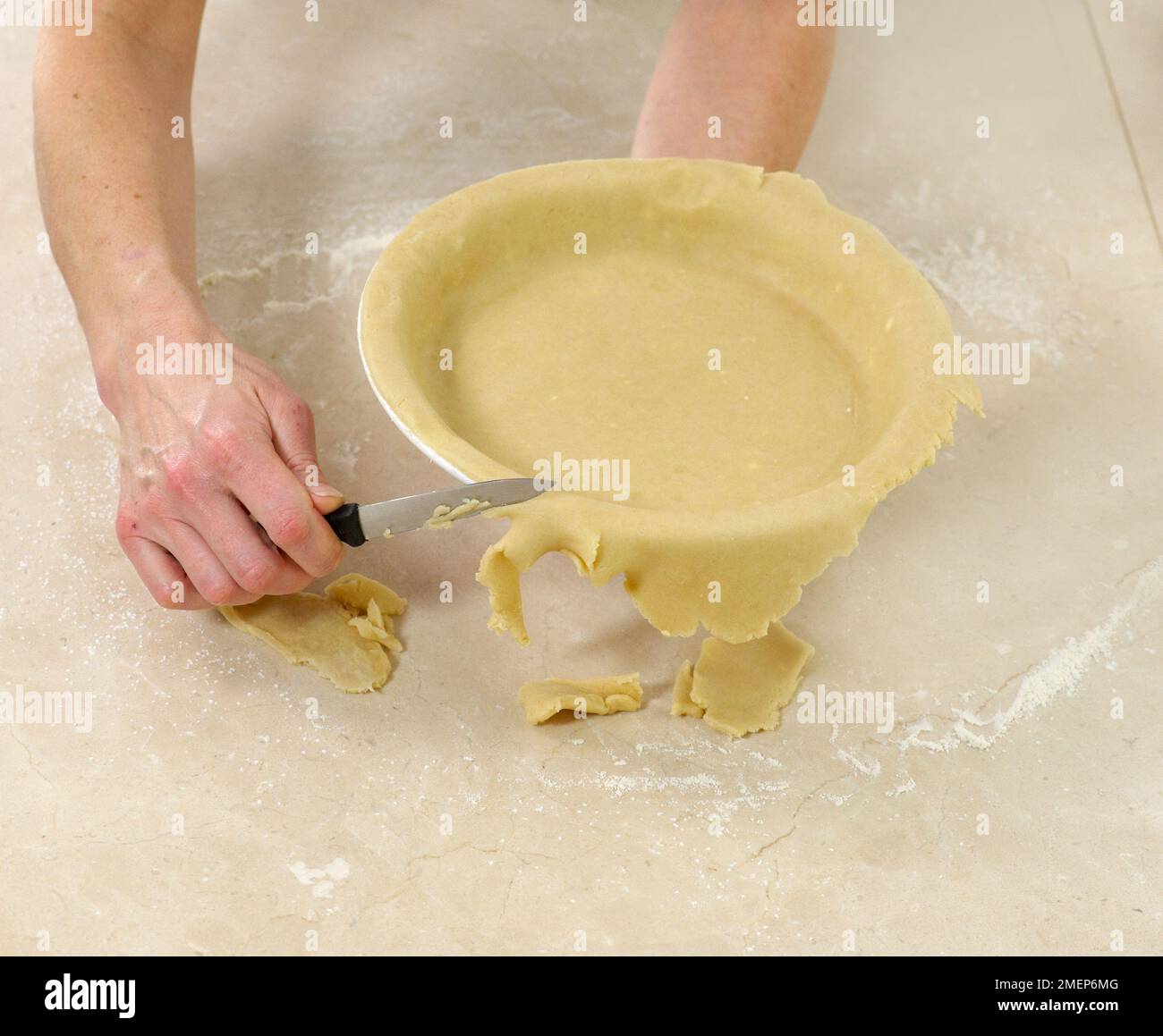 Using knife to trim edges of apple pie pastry in pastry dish Stock ...