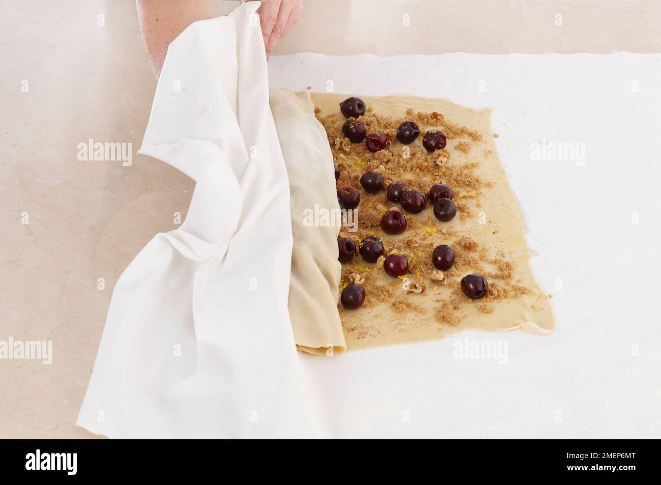 Cherry Strudel, rolling up strudel using a sheet Stock Photo - Alamy