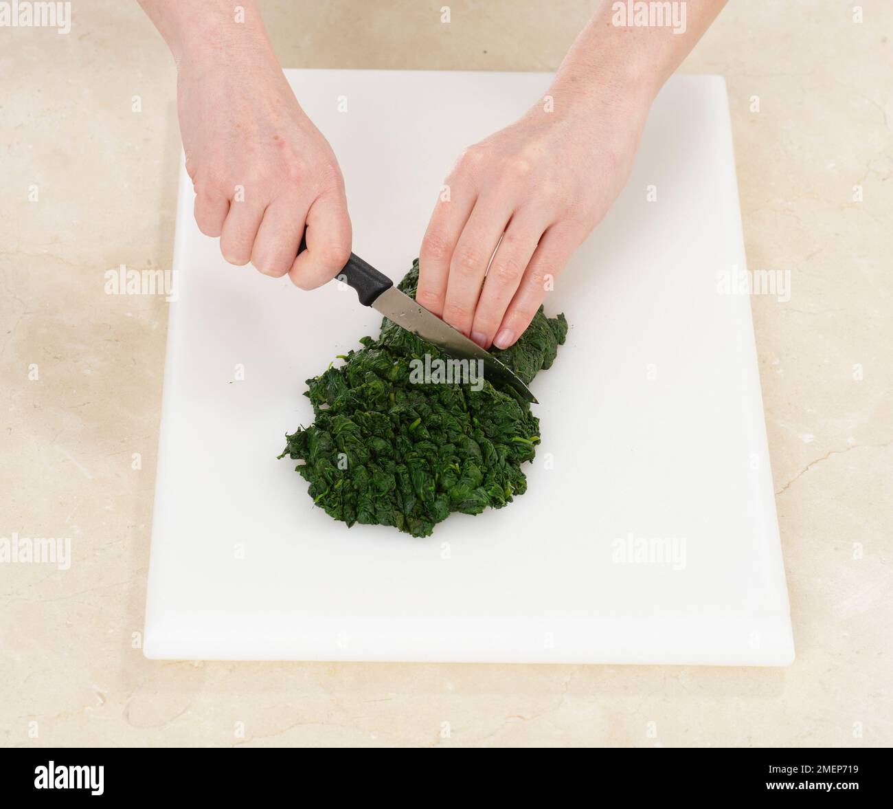 Chopping cooked spinach, to make filling for Filo Pie Stock Photo - Alamy