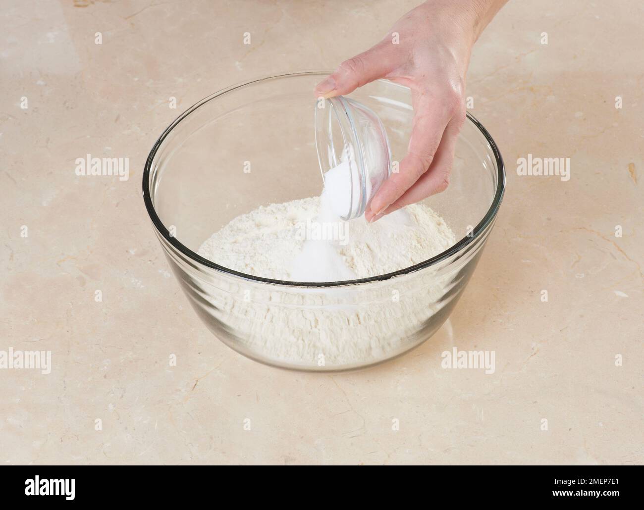 Pouring sugar into flour in glass mixing bowl Stock Photo - Alamy